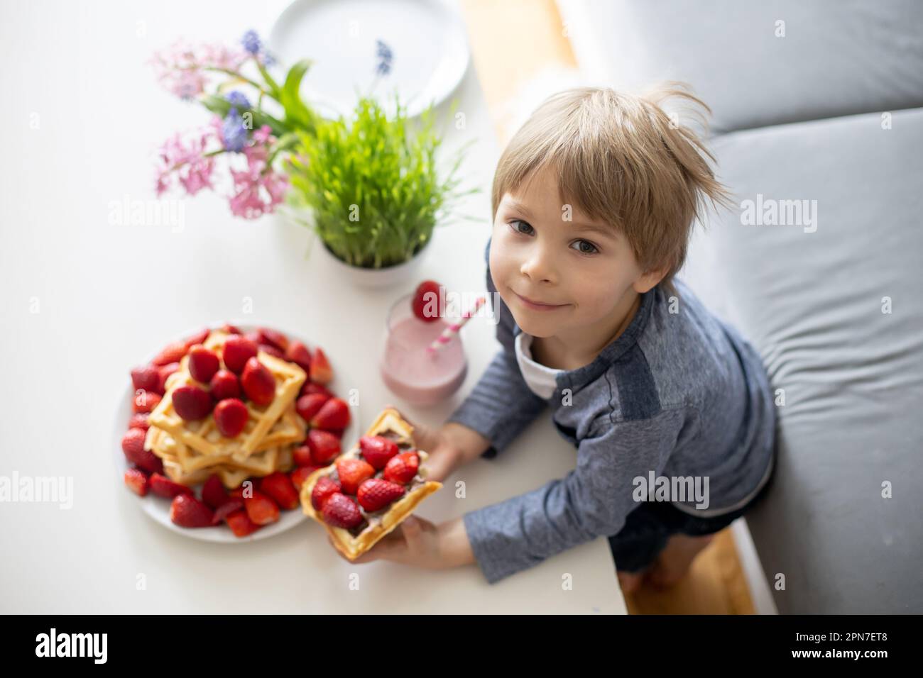 Sweet preschool child, boy, eating belgian waffle with strawberries and ...