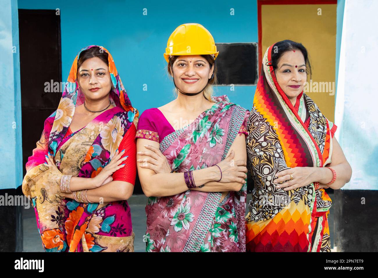 confident young indian female engineer wearing yellow hard hat and vest standing cross arms ...