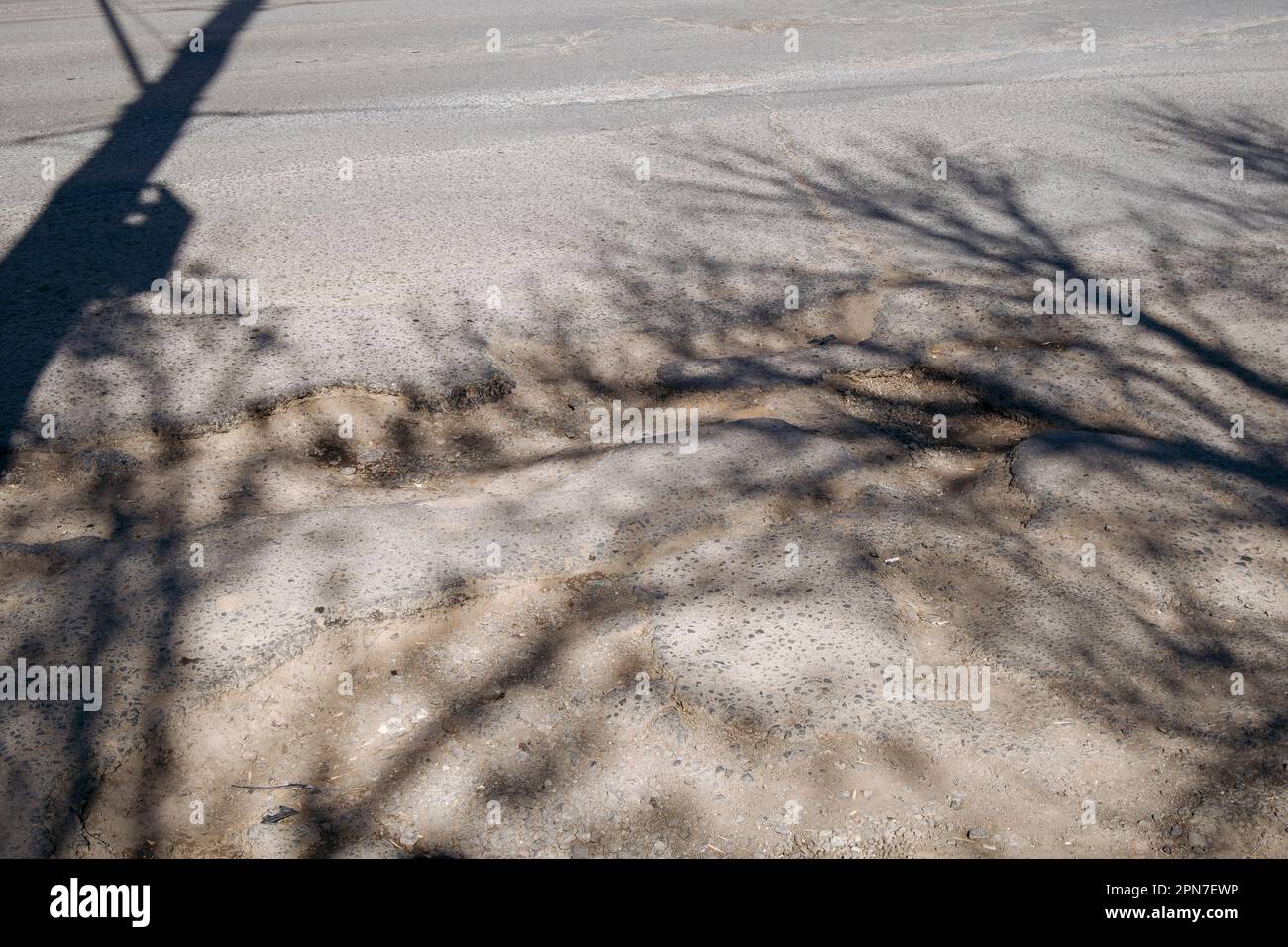 A highway with large pits and shadows from trees Stock Photo - Alamy