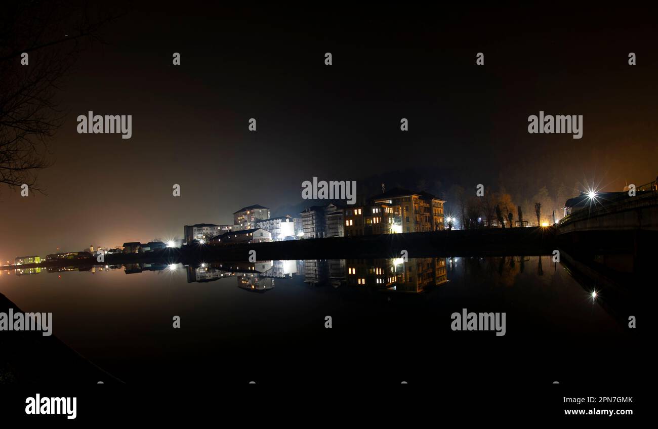 Night photo on the Olt valley - Romania with many buildings reflecting ...