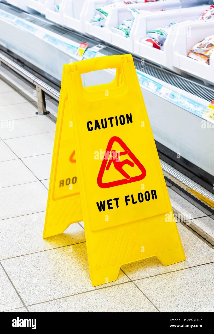 Caution Wet Floor yellow warning sign on a tile floor in a superstore ...