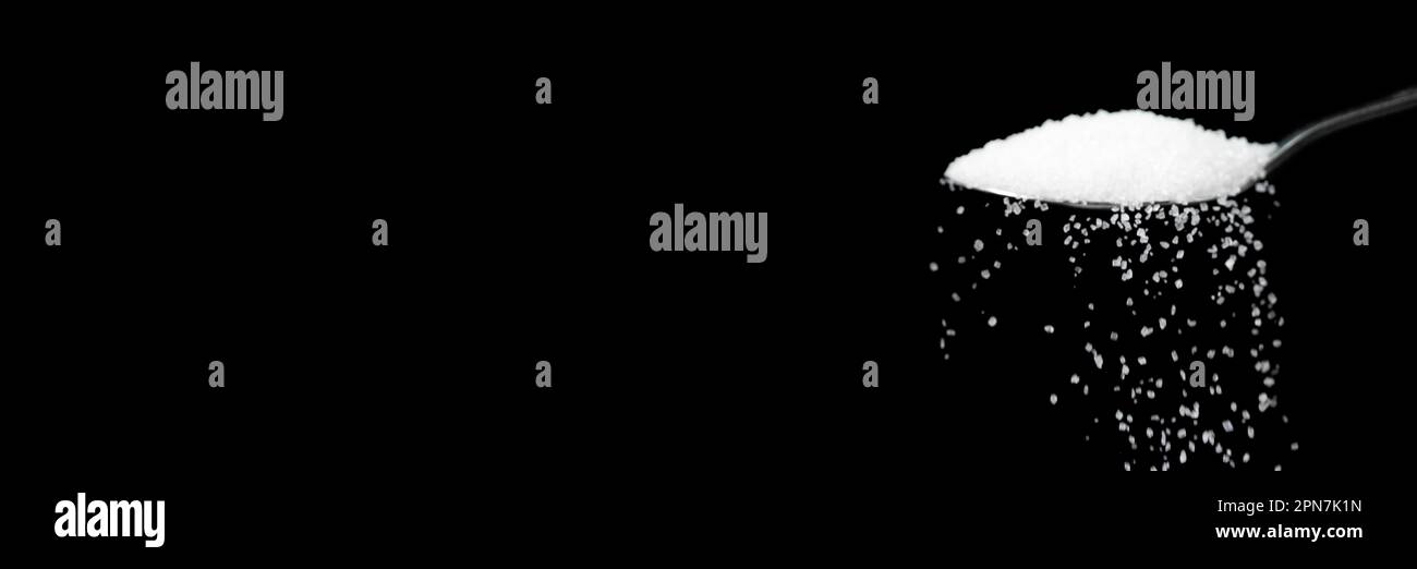 Macro photography of a teaspoon with white sugar on a black background ...