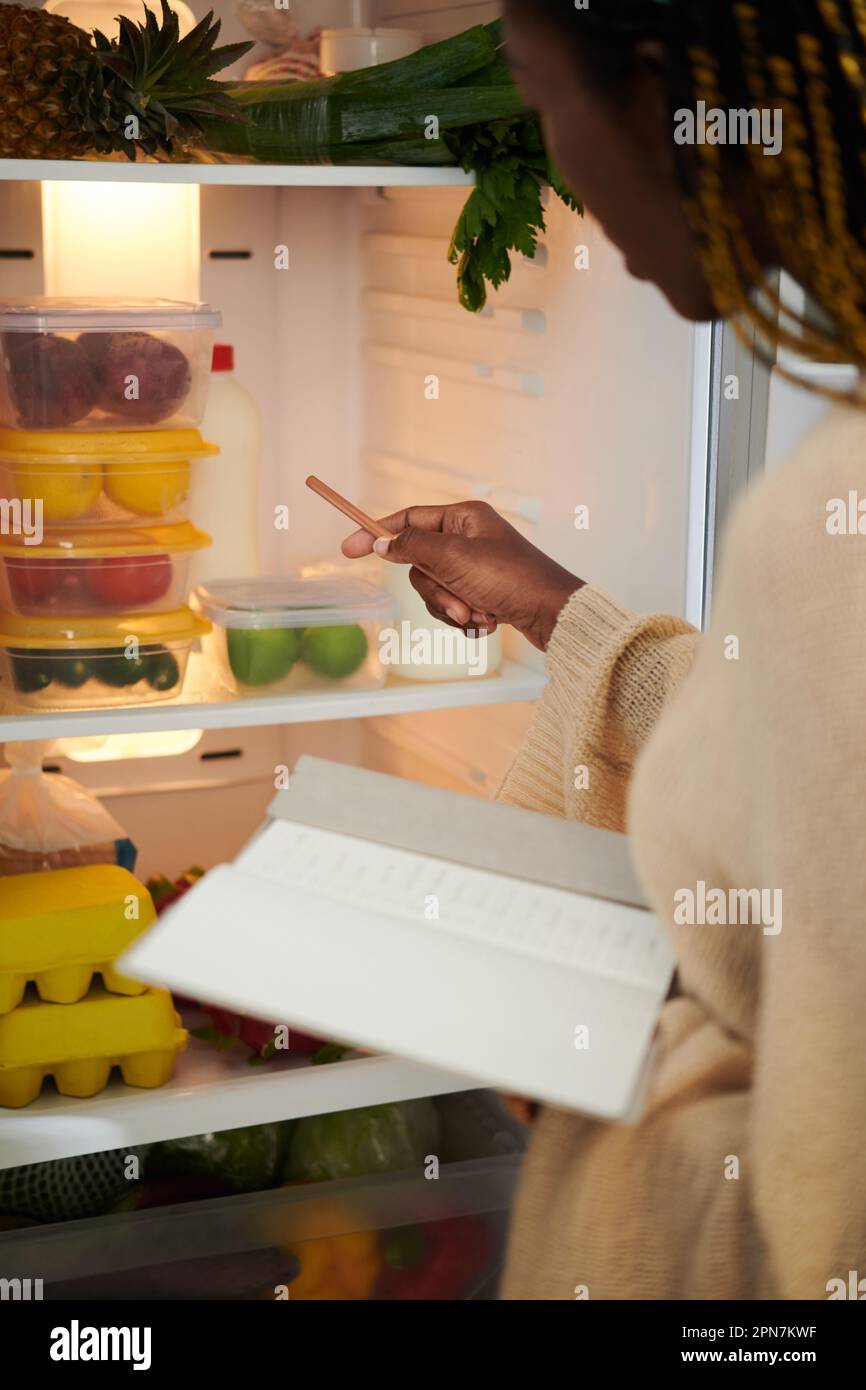 Woman opening fridge and writing down shopping list Stock Photo - Alamy