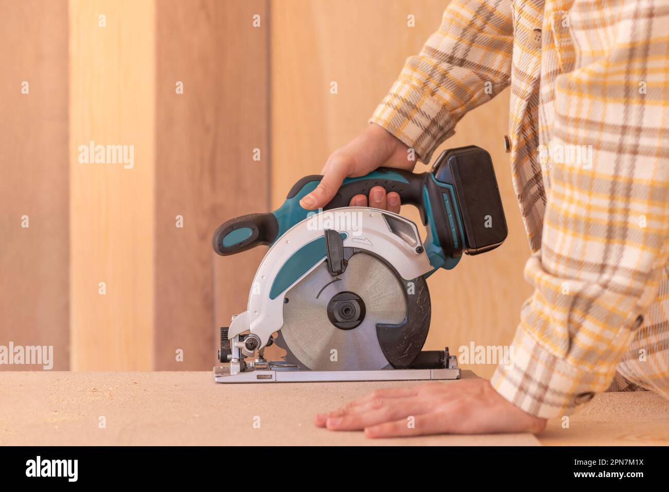 Side view of male carpenter in goggles cutting wooden board with ...