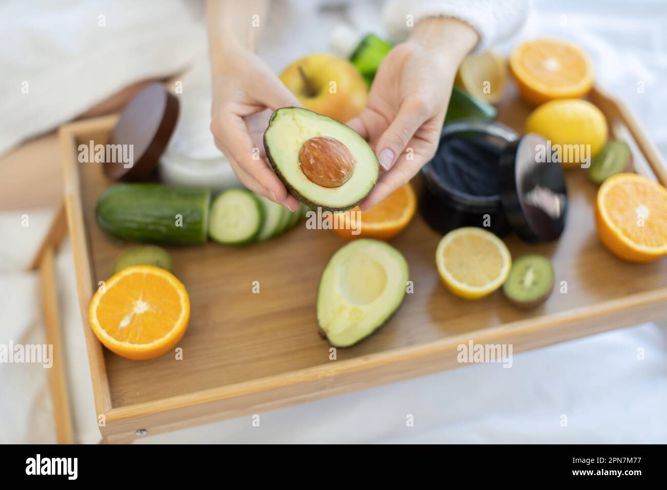 Close-up view of green avocado in woman hands being held above sliced ...