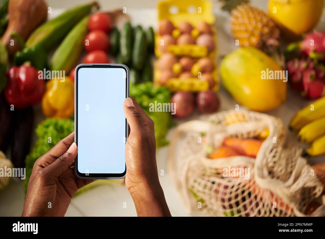 Hands holding smartpone with empty screen over counter with fresh ...