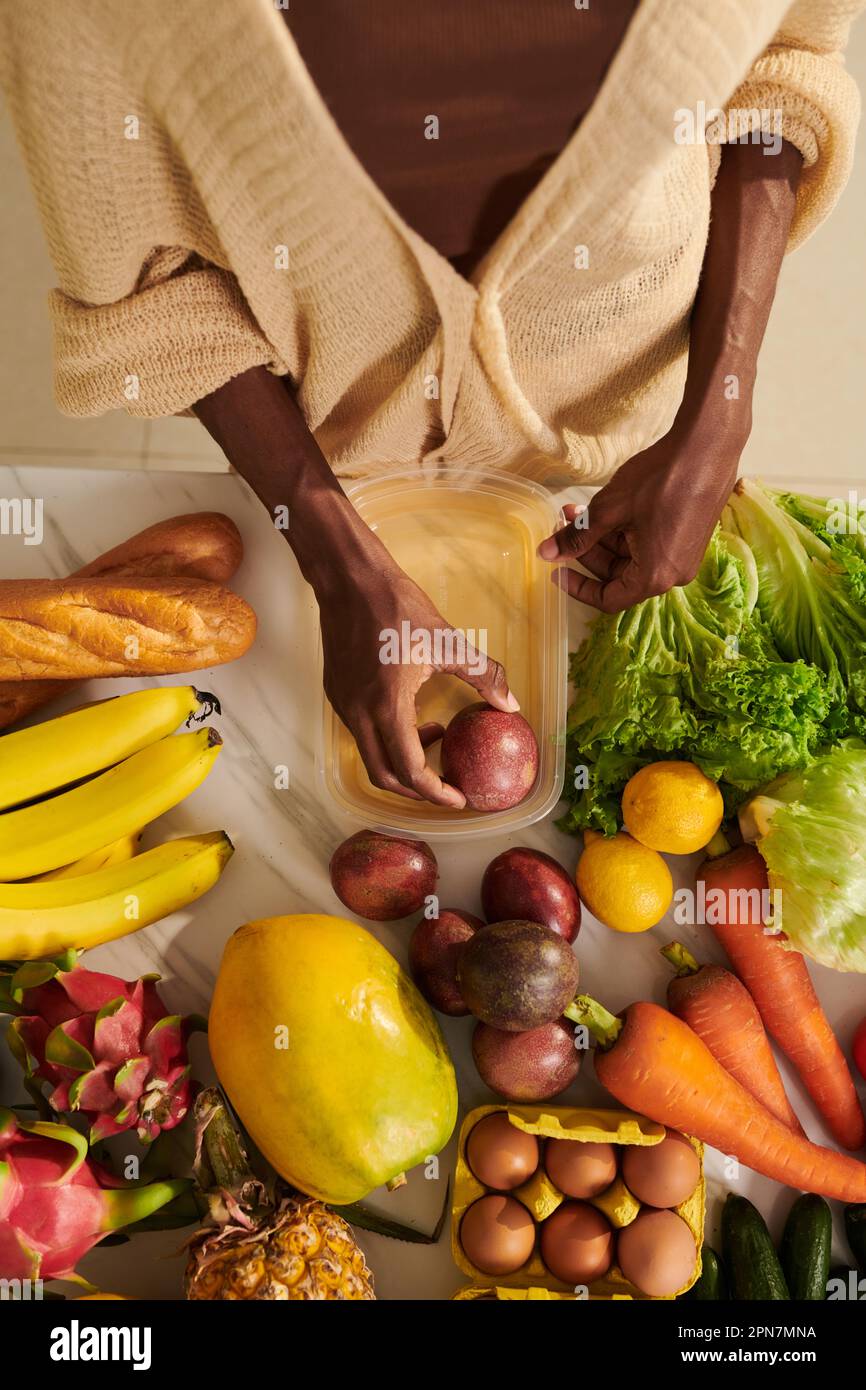 Woman packing fresh fruits and vegetables in plastic containers to ...