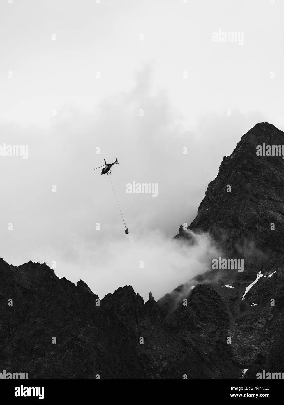 Helicopter in the swiss mountains, flying into bad weather Stock Photo ...