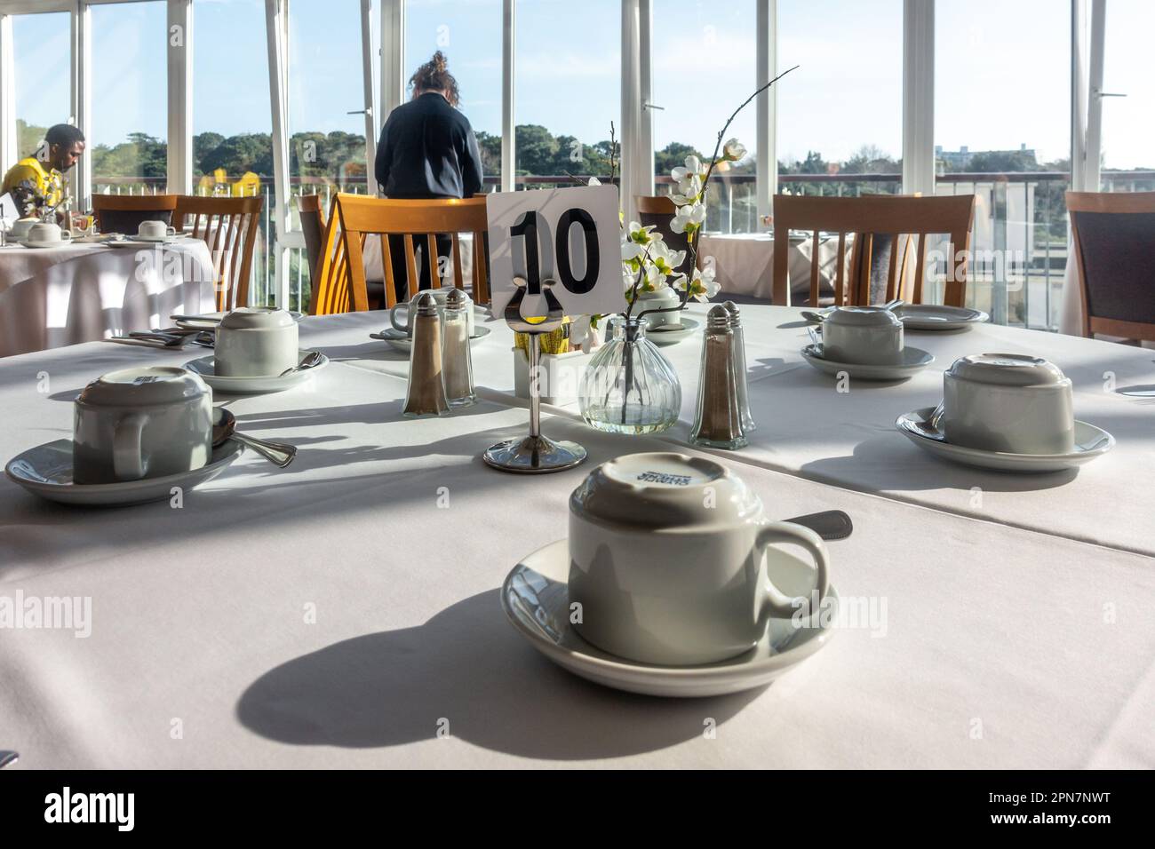 Table 10 in a hotel restaurant set up with clean tablecloth and mugs ...