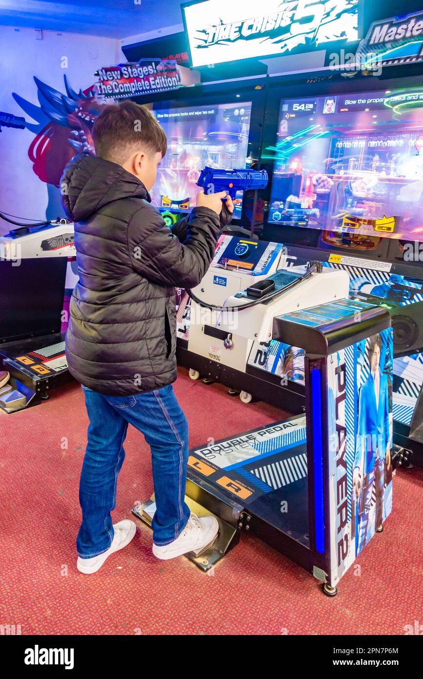 A boy playing a shooting video game, aiming a blue, plastic fun in an ...
