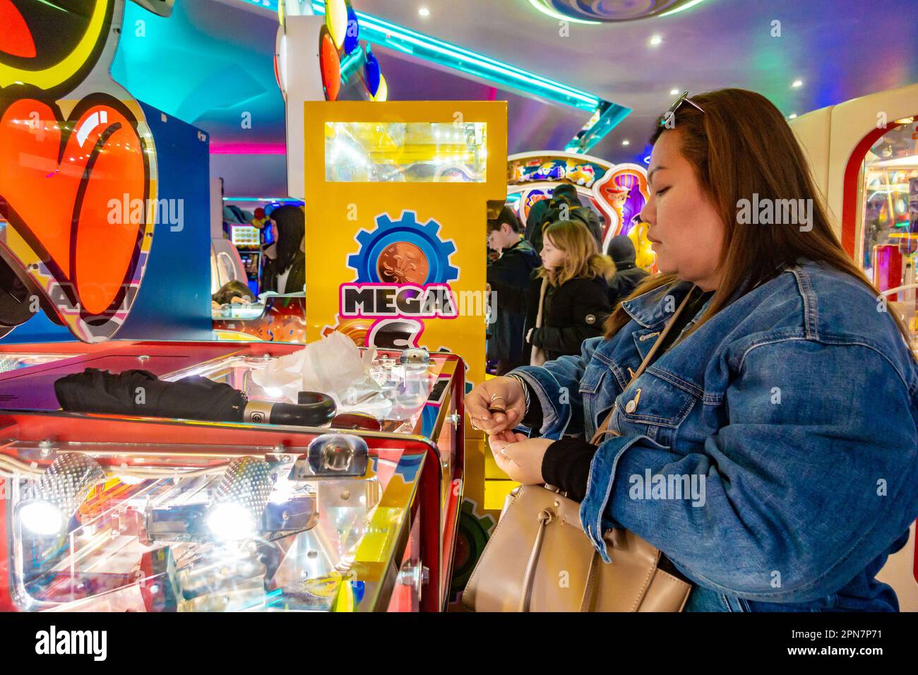 A lady concentrating, playing a penny falls machine in an arcade in ...