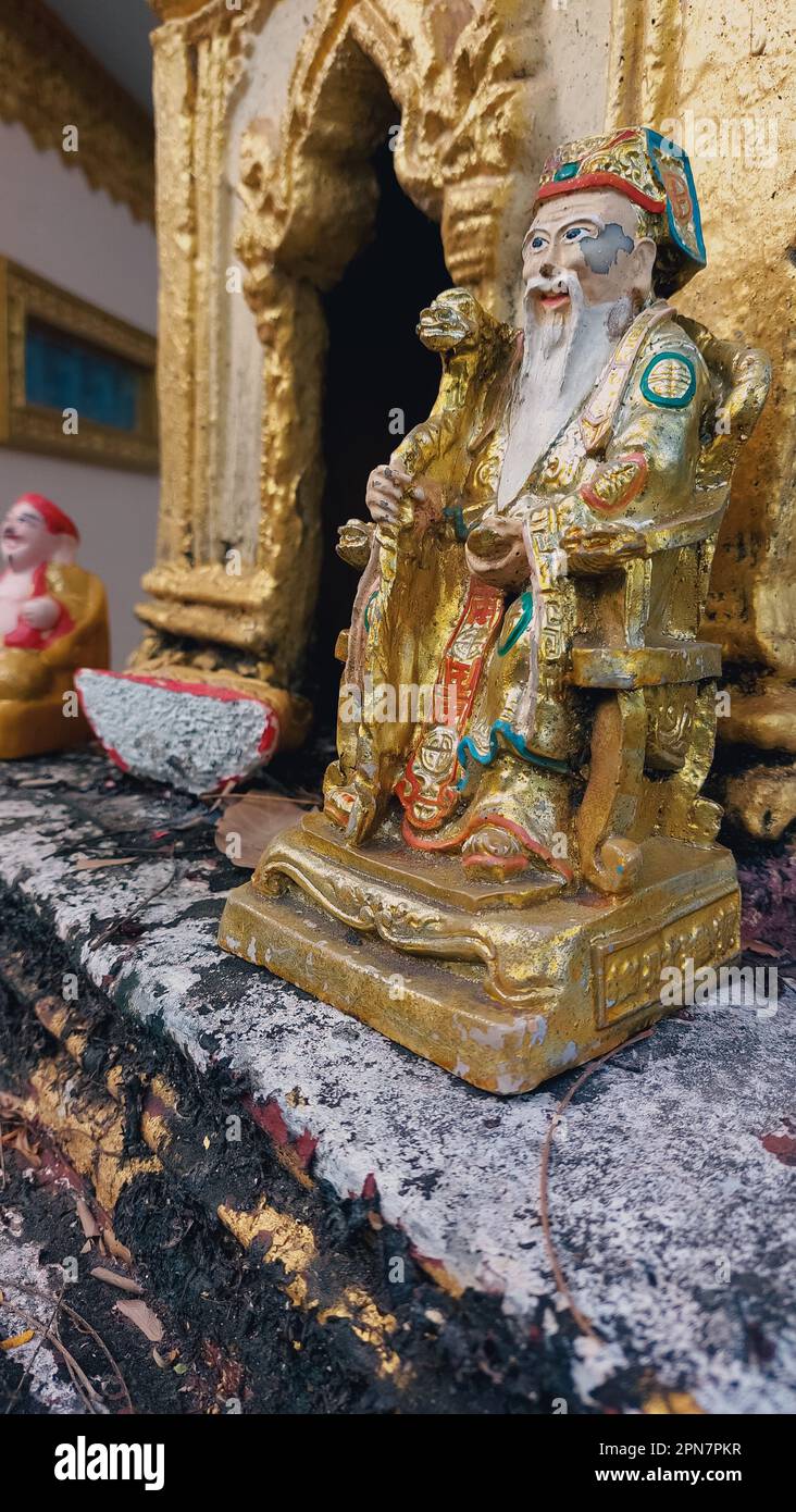 An ornate golden statue of Confucius in a traditional Khmer shrine in ...