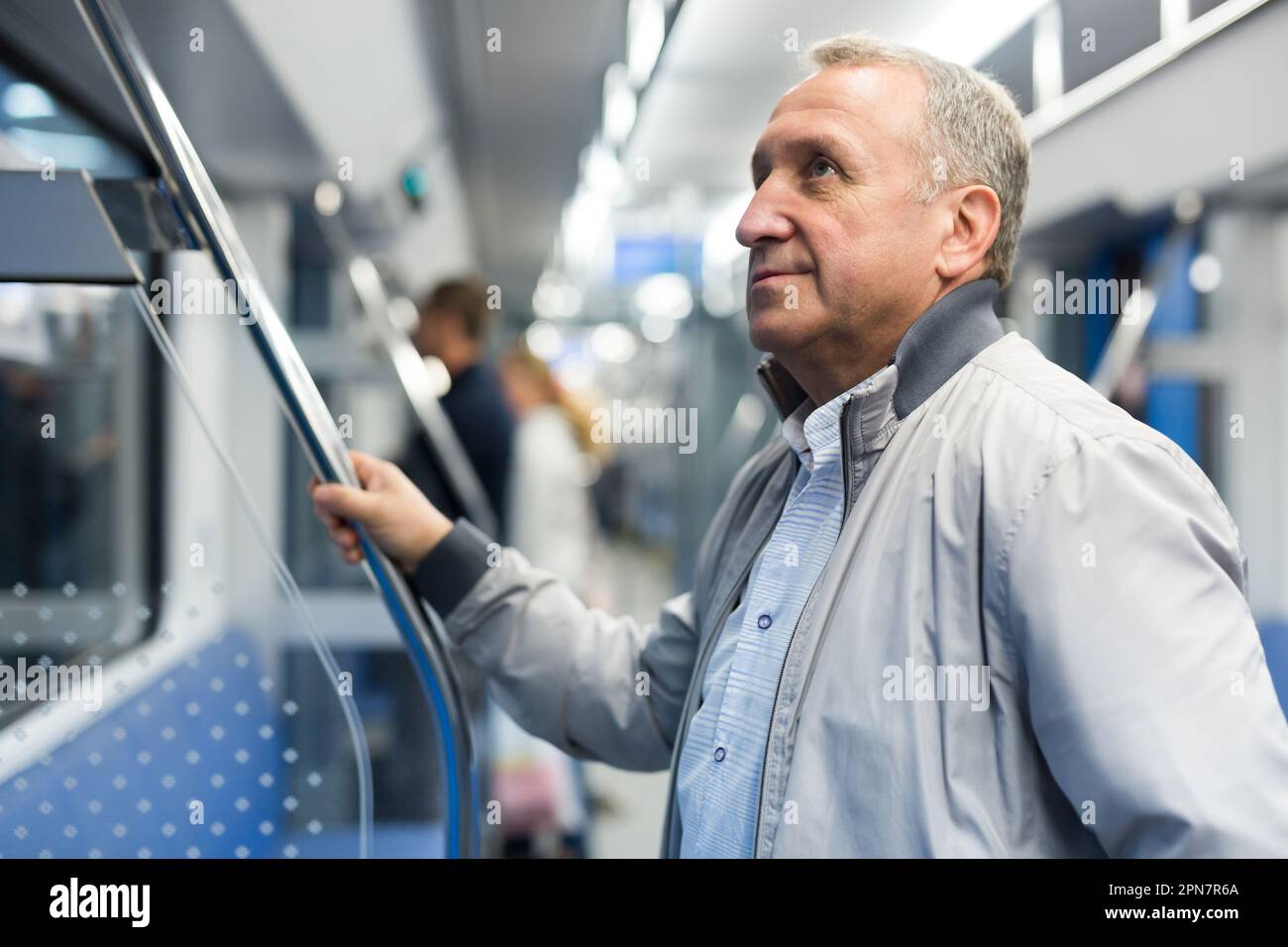 Mature man standing in subway and holding handrail Stock Photo - Alamy