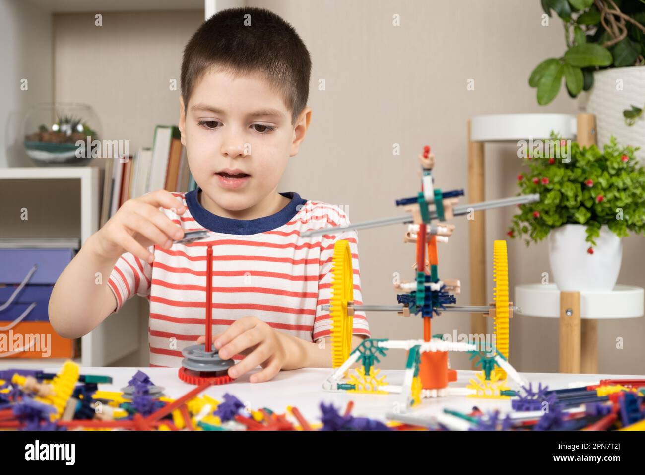 A little boy plays with a constructor, creating figures from gears and ...