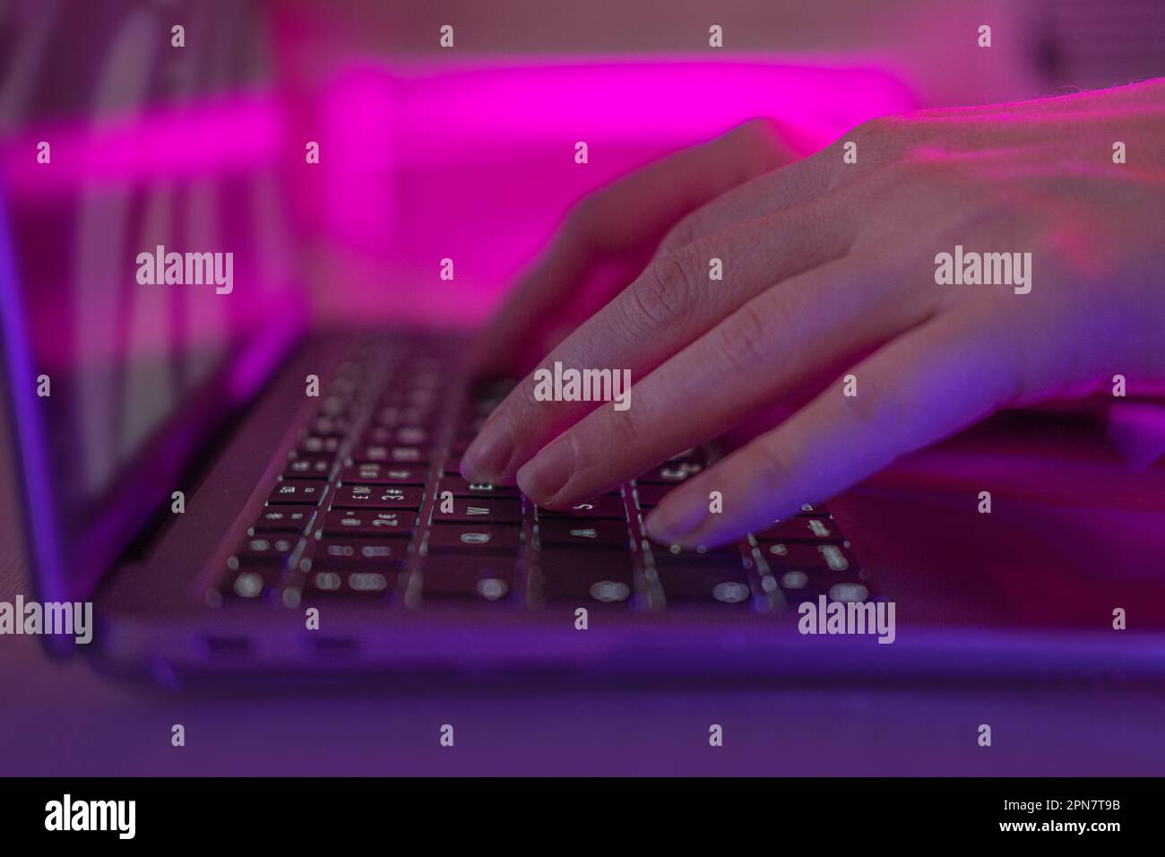 Person typing at laptop computer at night. Female uses keyboard, shakes ...
