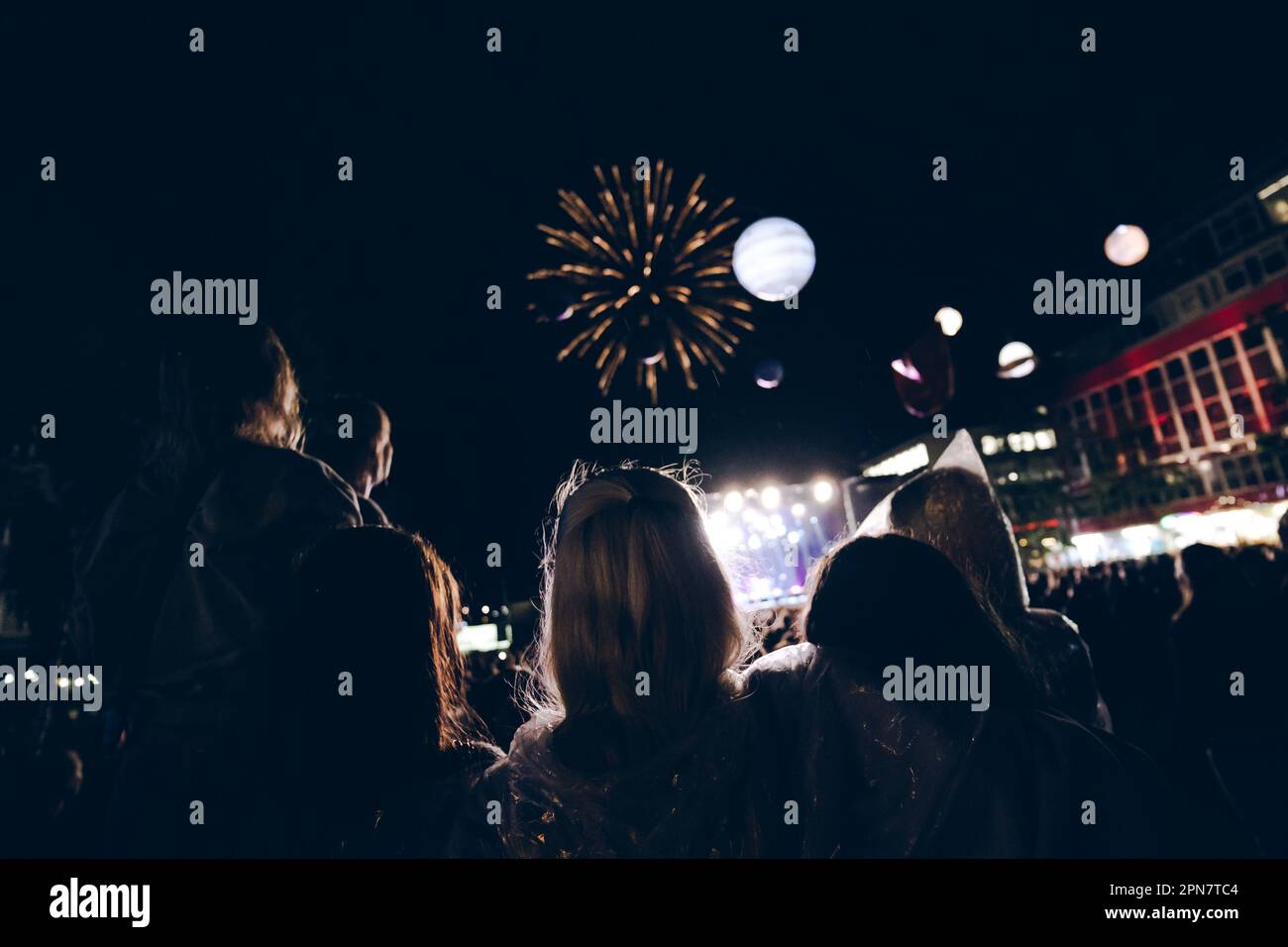 A group of people stands in awe of the vibrant display of fireworks ...