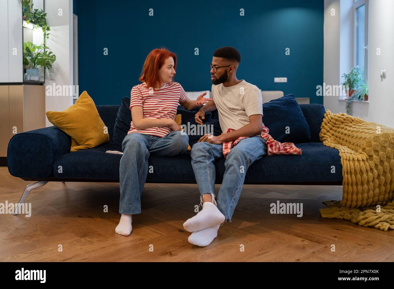 Emotional multi ethnic annoyed stressed couple sitting on couch arguing ...