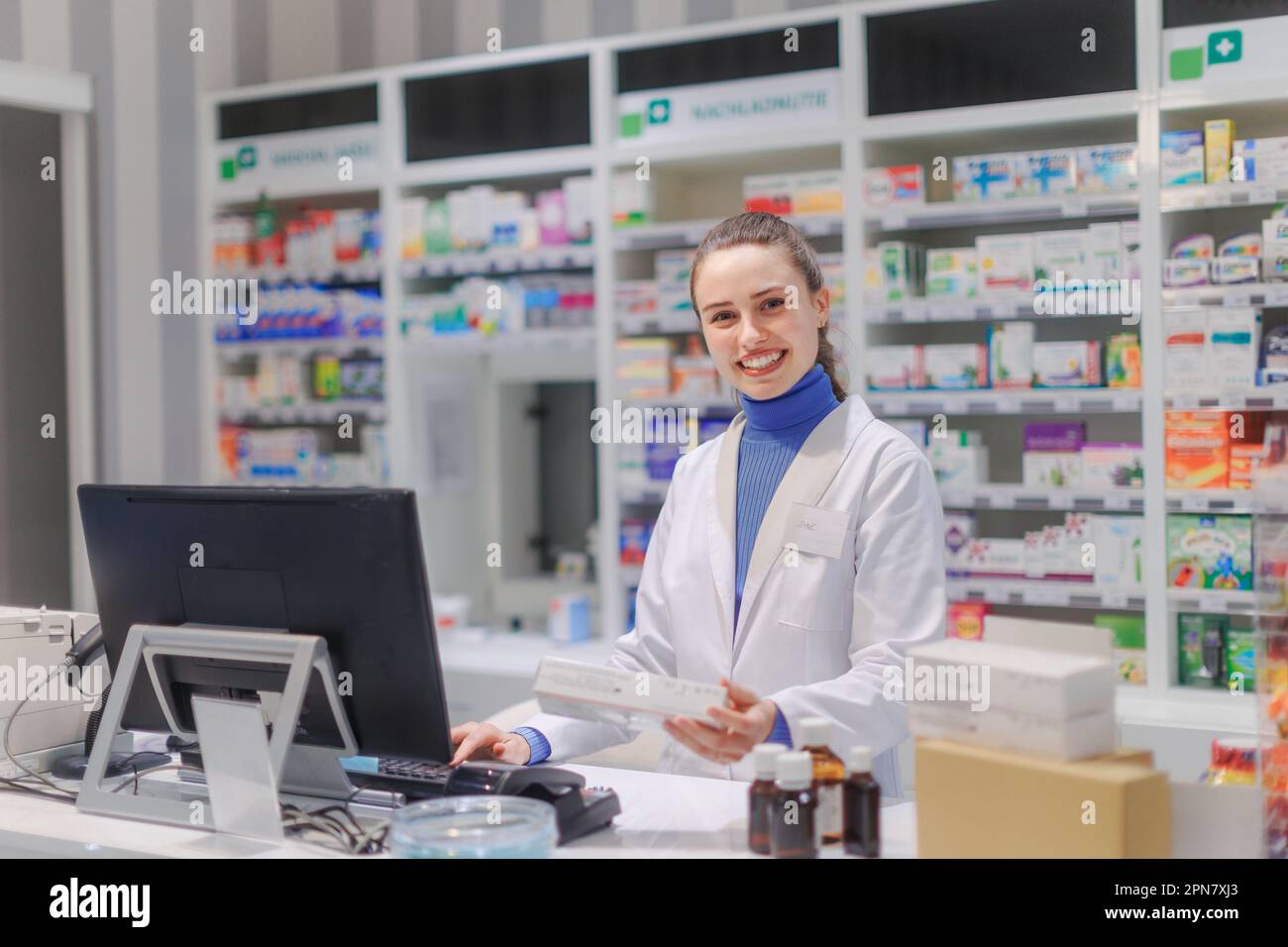 Portrait of young pharmacist selling medication in pharmacy Stock Photo ...