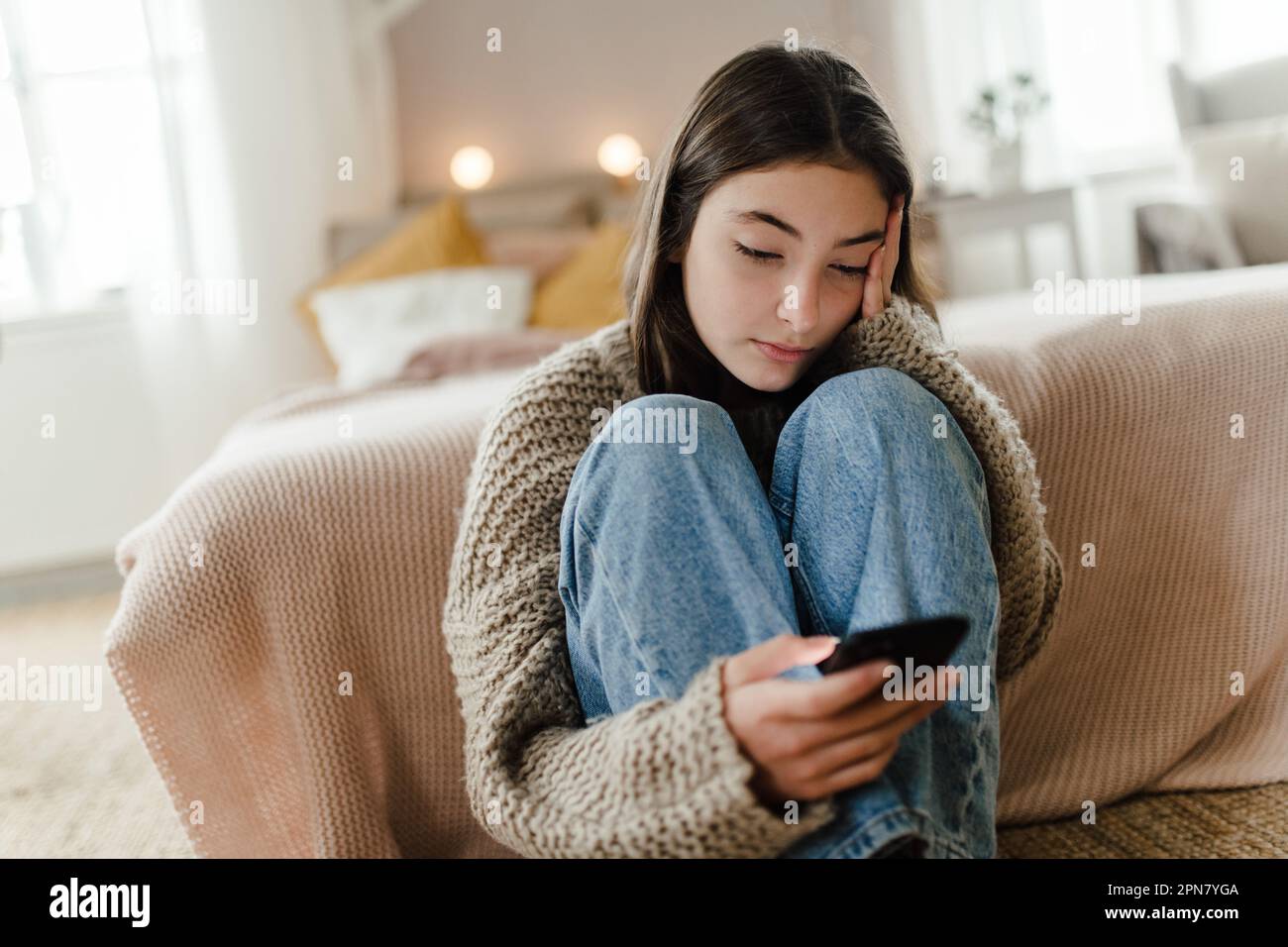 Teenage girl sitting on the floor and scrolling her smartphone Stock Photo - Alamy