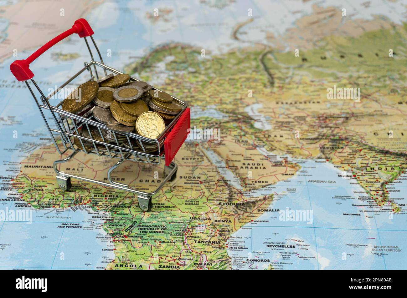 A supermarket cart full of coins. On the background is a map of the ...