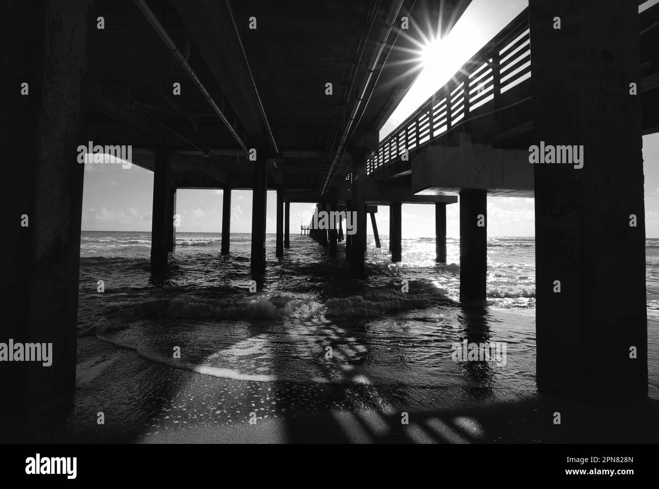 An atmospheric, high-contrast black and white image of a wooden pier ...