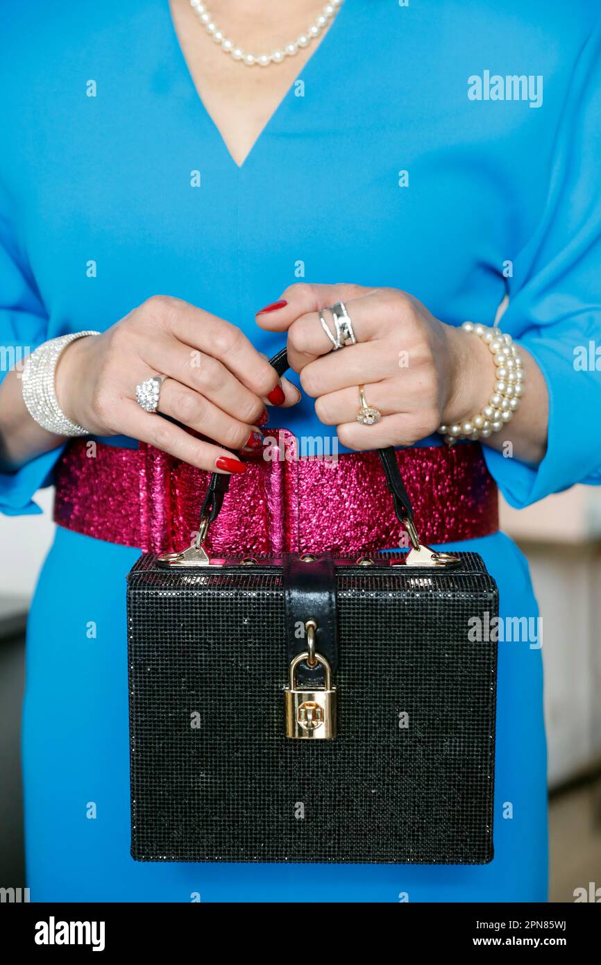Woman wearing a blue dress holding a classy black bag Stock Photo - Alamy