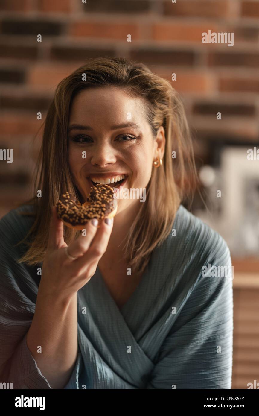 Young happy woman eating donuts in a cafe Stock Photo - Alamy