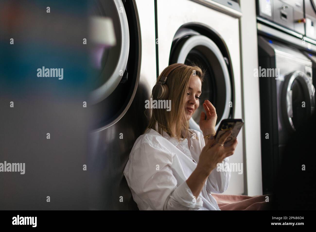 Young woman listening music, waiting in a laundry room Stock Photo - Alamy