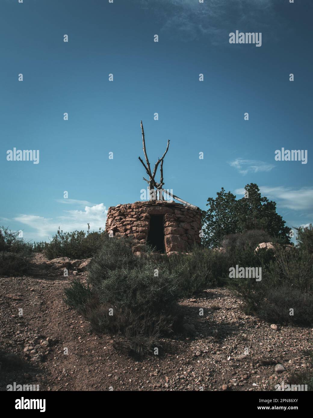 A rustic rock hut located in a desert landscape, surrounded by a sparse ...