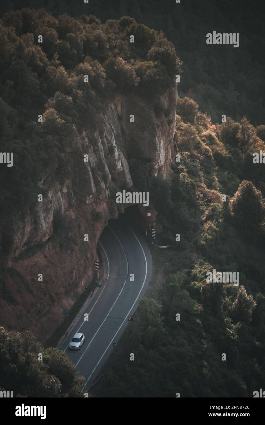 A white car driving along a scenic mountain road, passing lush ...