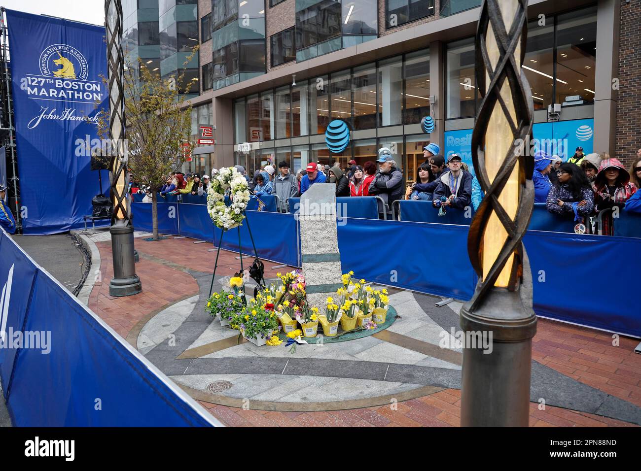 Spectators look on near a memorial at the site of the first bomb to go ...