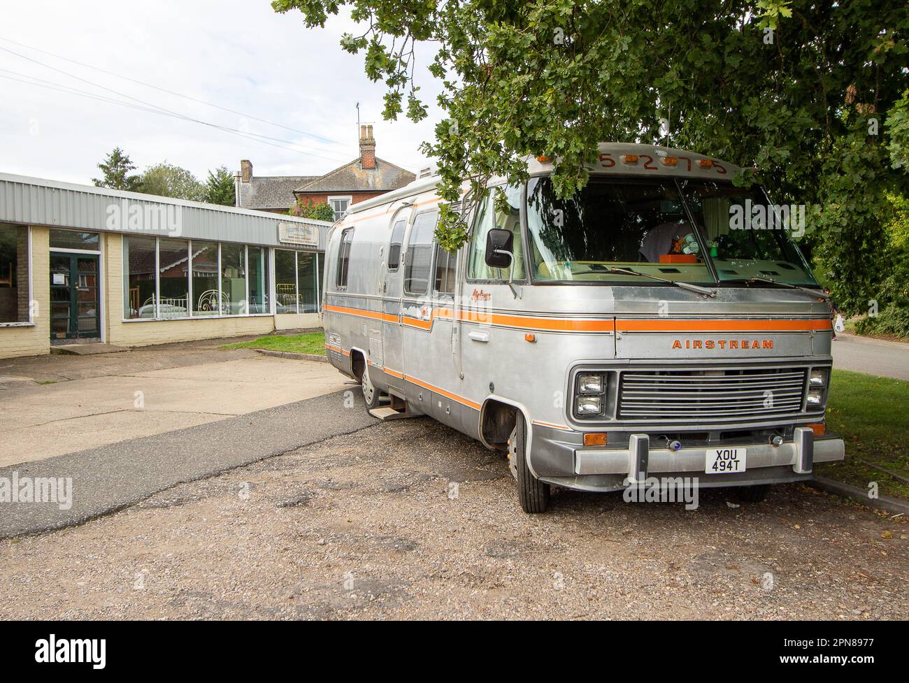 An Airstream mobile home parked under an oak tree and in front of low ...