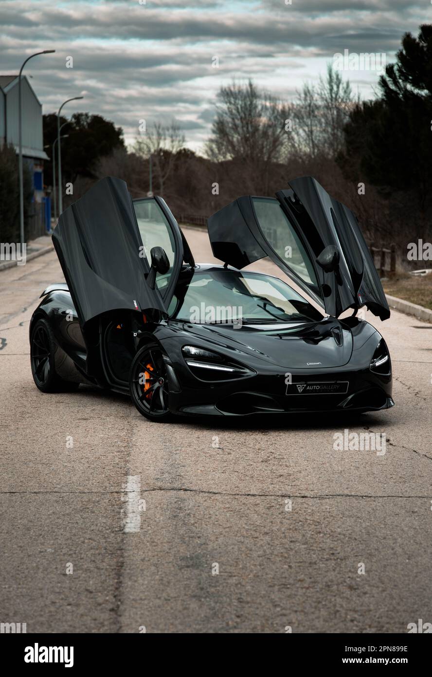 A sleek and stylish McLaren sports car sits on a roadway with the doors ...