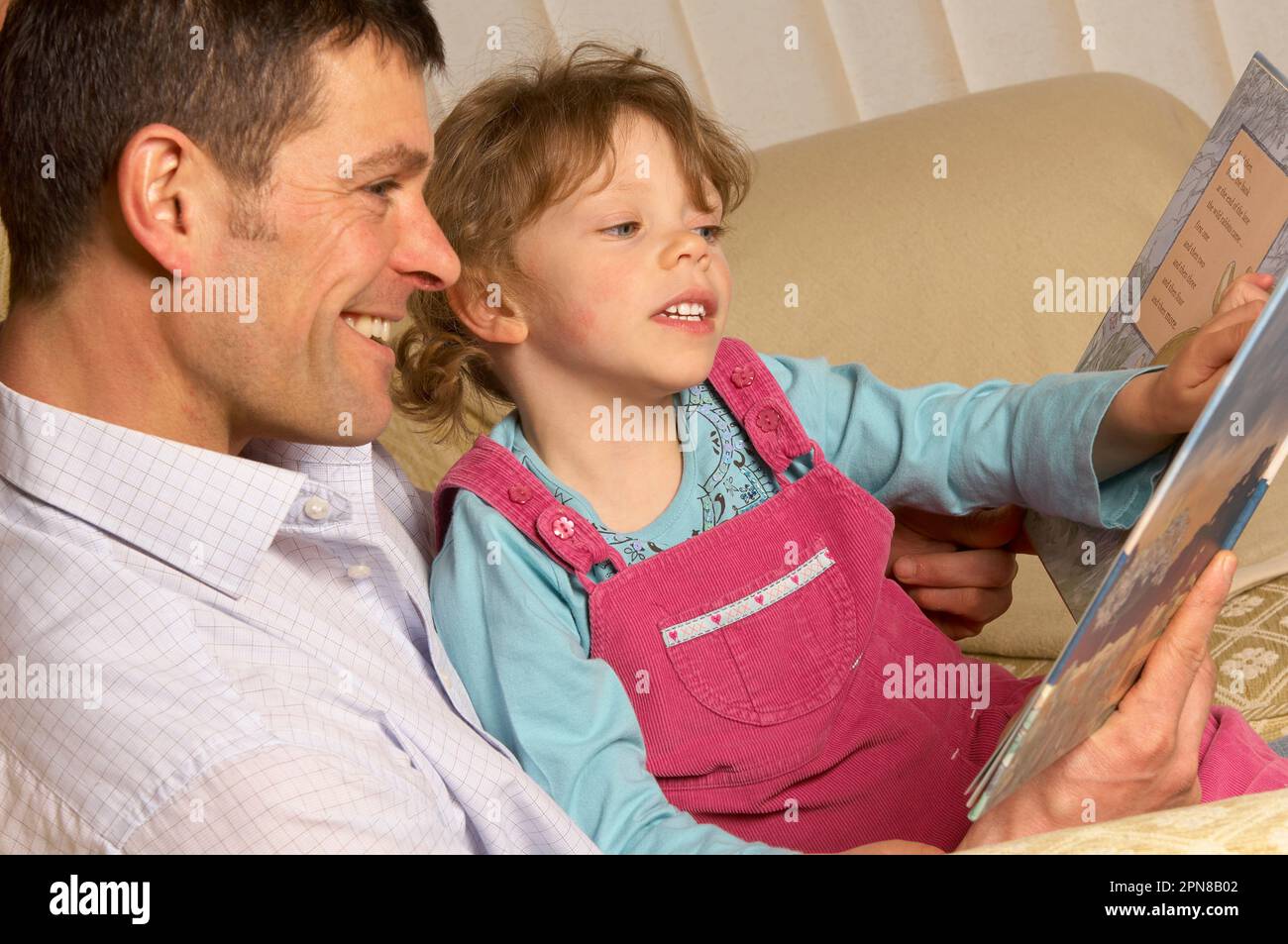 Young girl learning to read with her father at home Stock Photo - Alamy