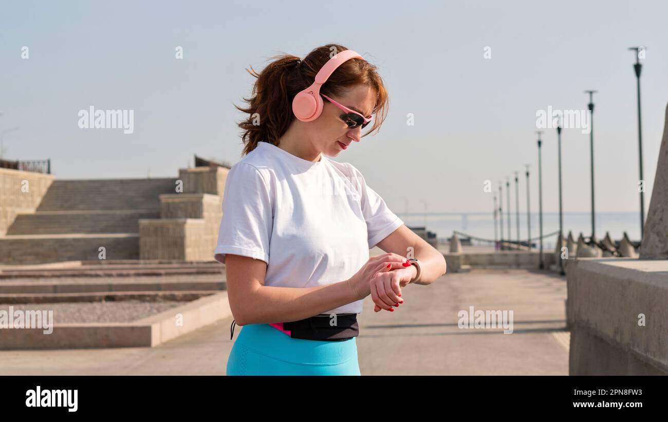 Female athlete runner checks time from smart watch. Young fit woman ...