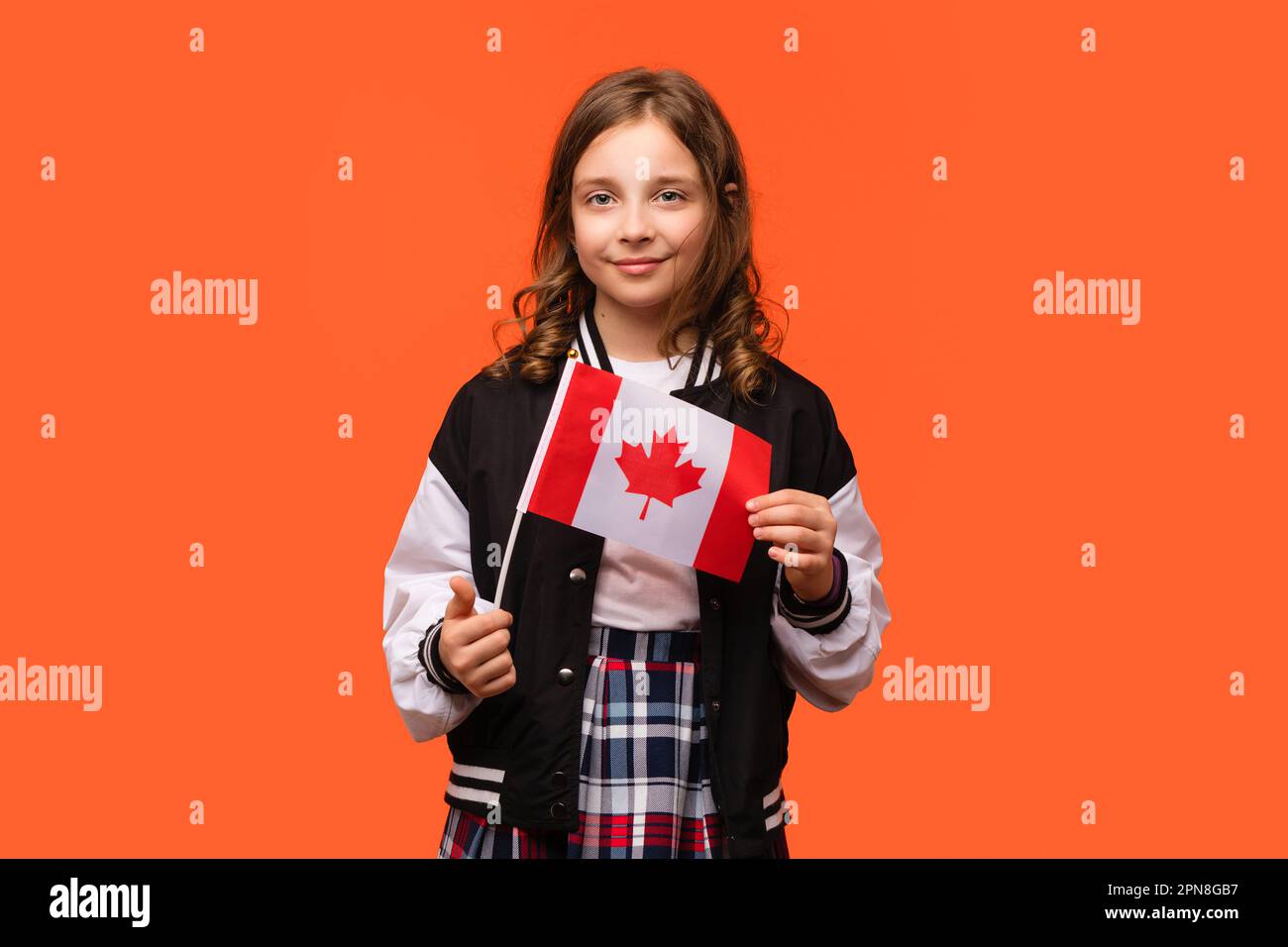 Girl wearing in school outfit and holds small national Flag of Canada ...