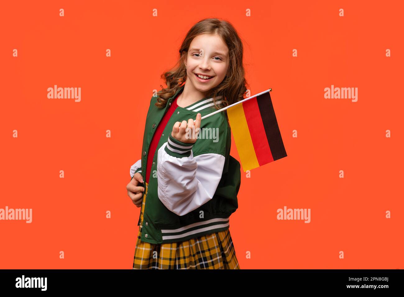 Girl wearing in school outfit and holds small national flag of Germany ...