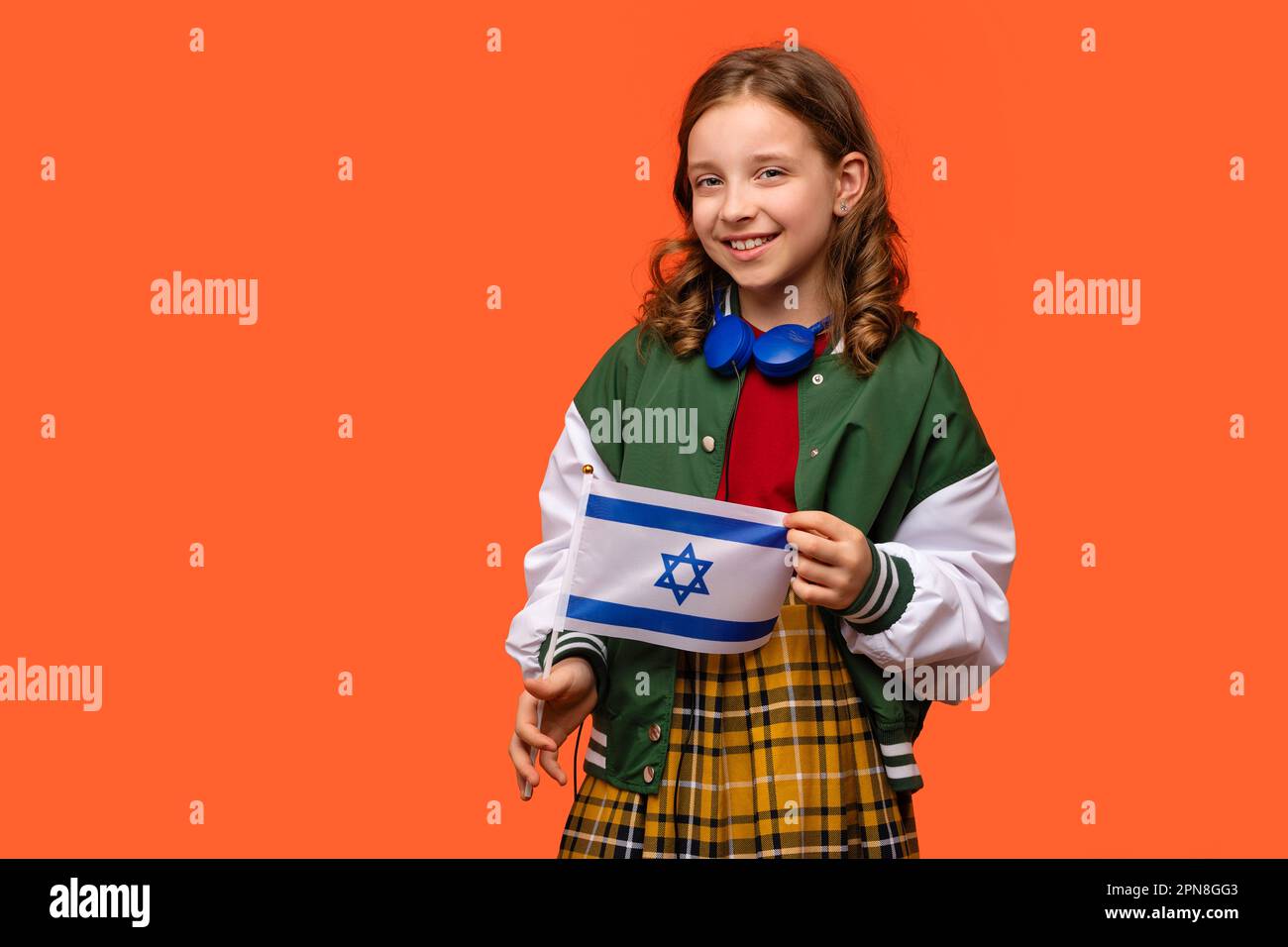 Teen girl in school outfit and blue headphones holds small flag of ...