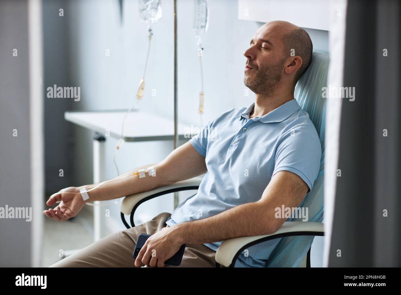 Side view portrait of adult man sitting in comfortable chair with IV ...
