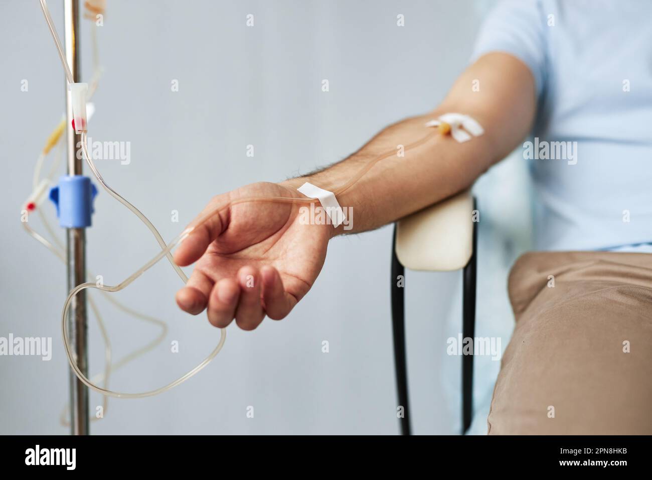 Minimal closeup of male arm with IV drip infusion in treatment session ...