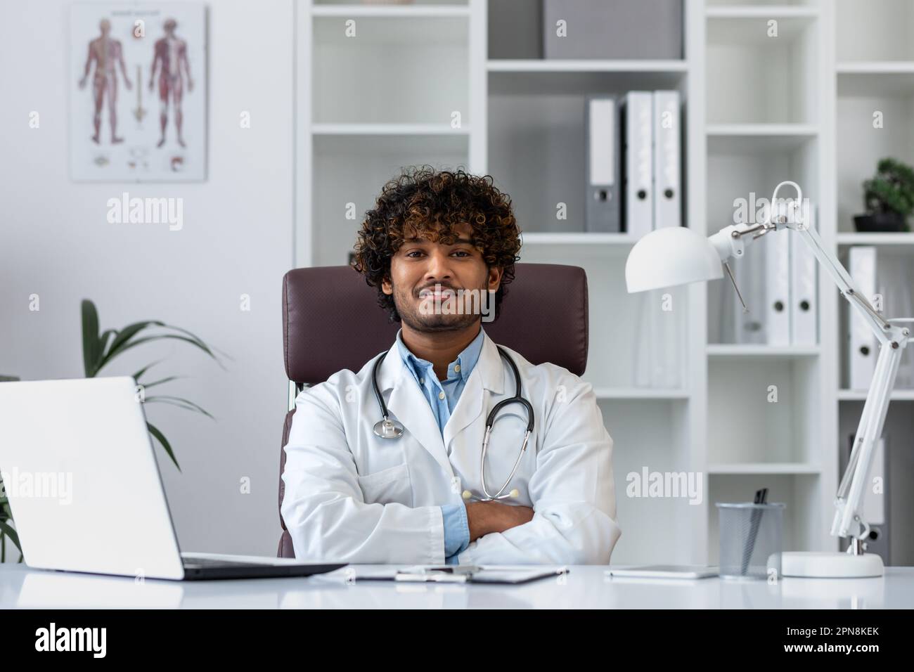 Portrait of a successful Hindu doctor inside the office of a modern ...