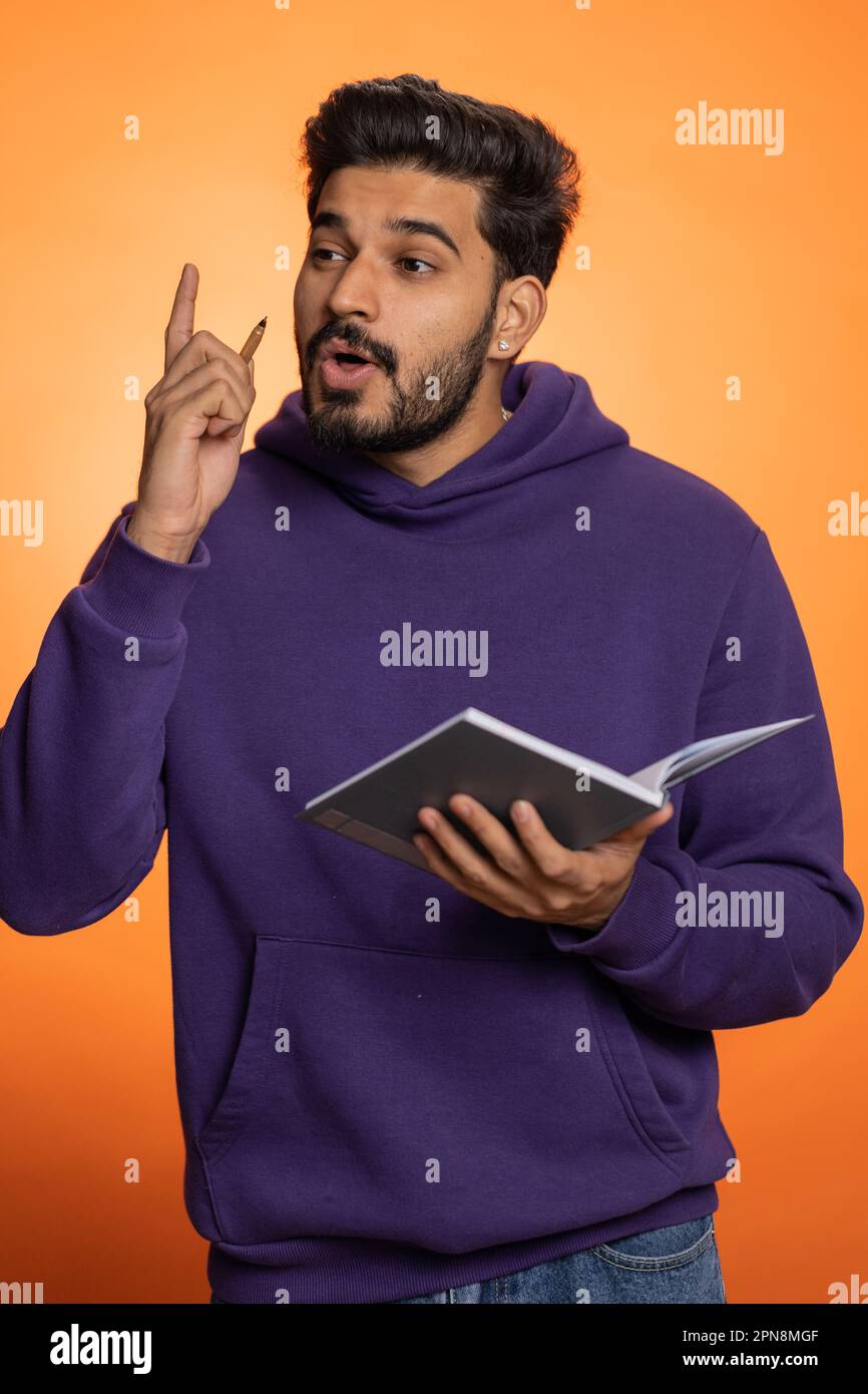 Thoughtful journalist indian man making notes, writing down thoughts ...