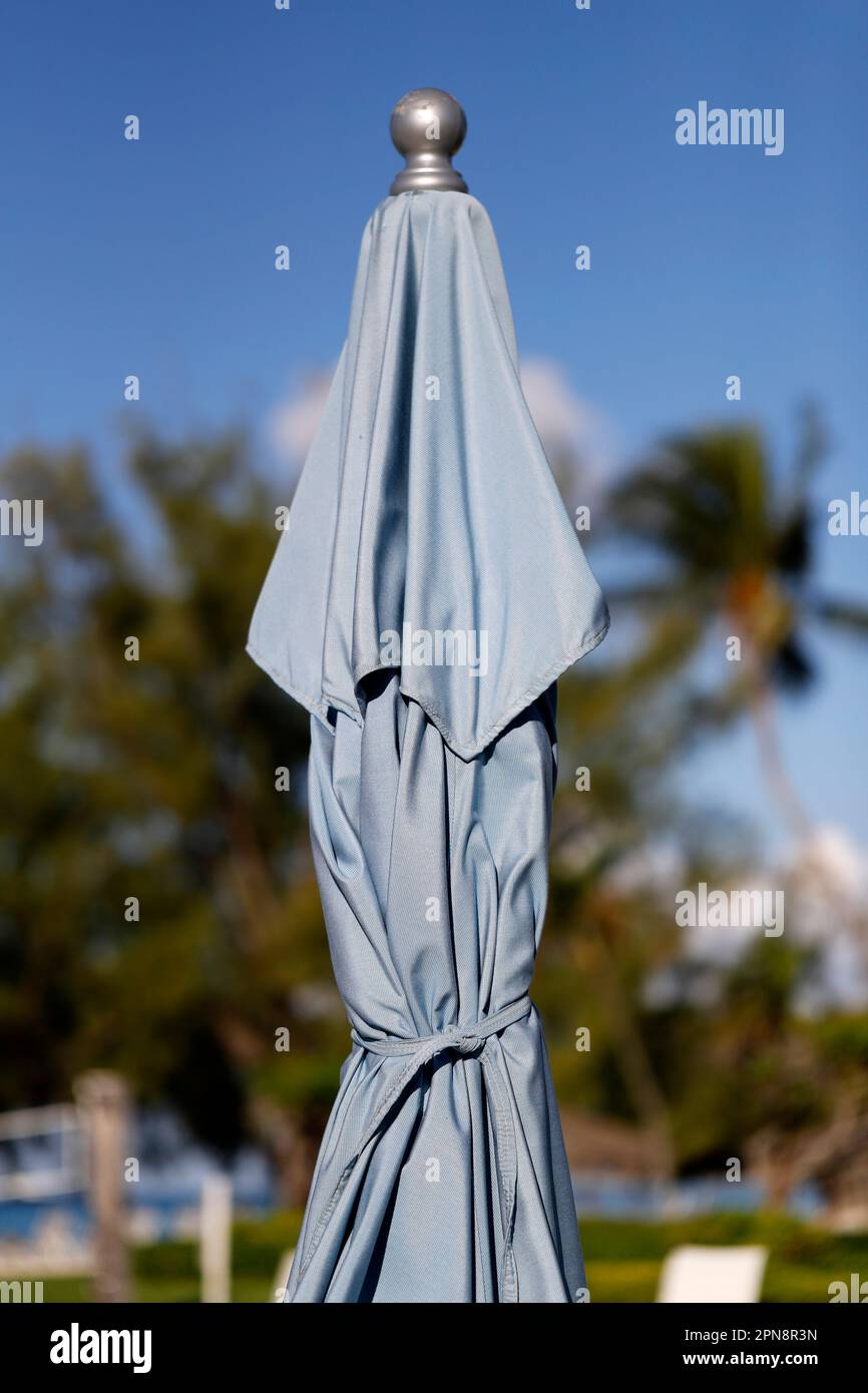 Fragment of folded blue textile umbrella parasol at swimming pool ...