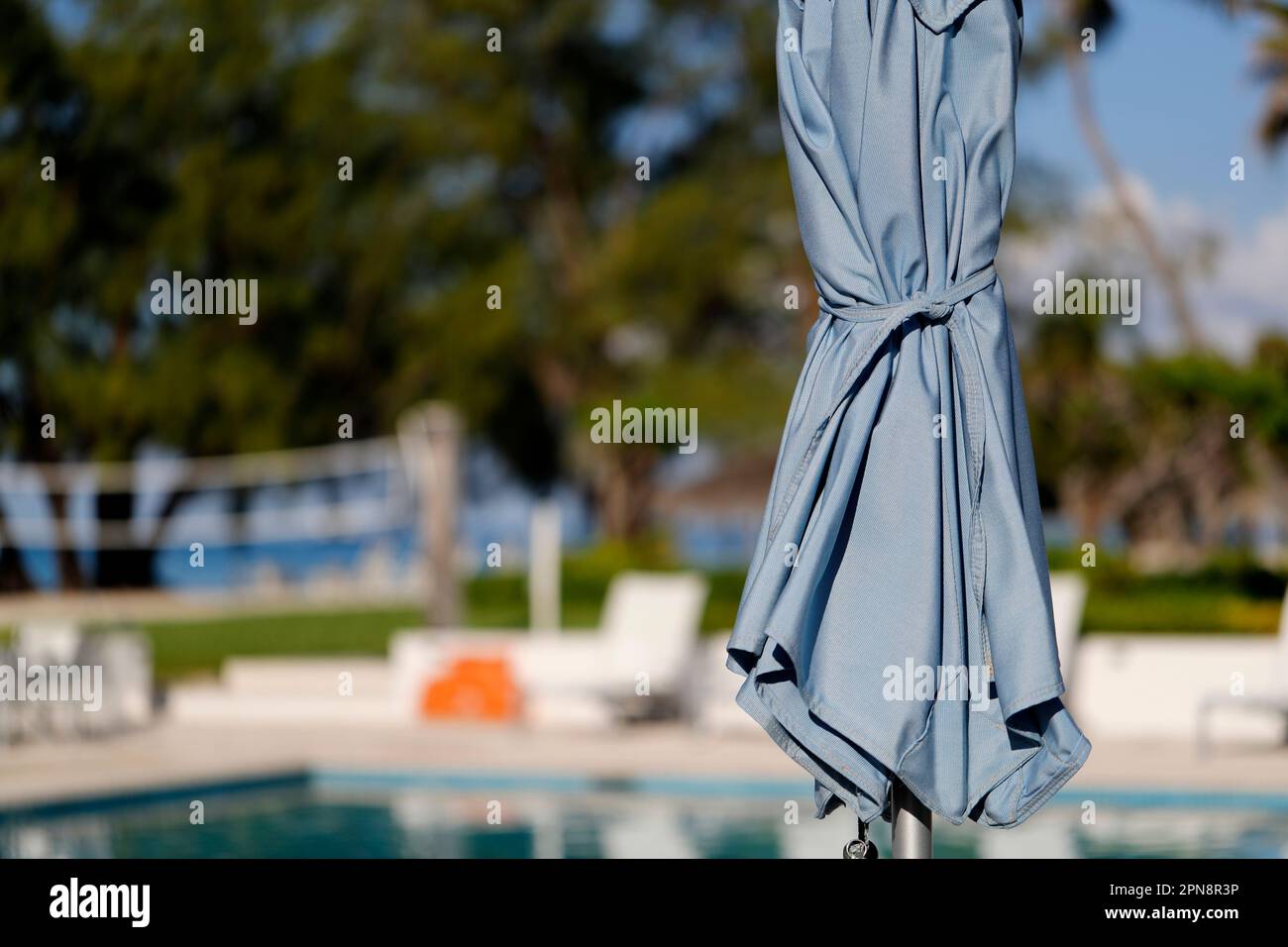 Fragment of folded blue textile umbrella parasol at swimming pool ...
