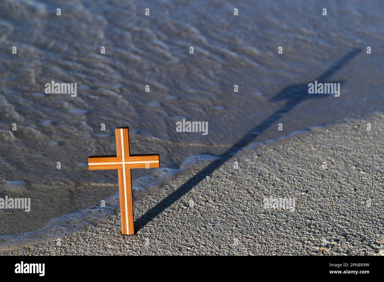 A wooden cross in the sand with shadow. Concept for religion, faith ...