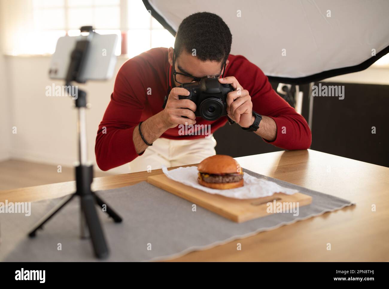 Food photographer taking photo of hamburger, using camera and phone ...