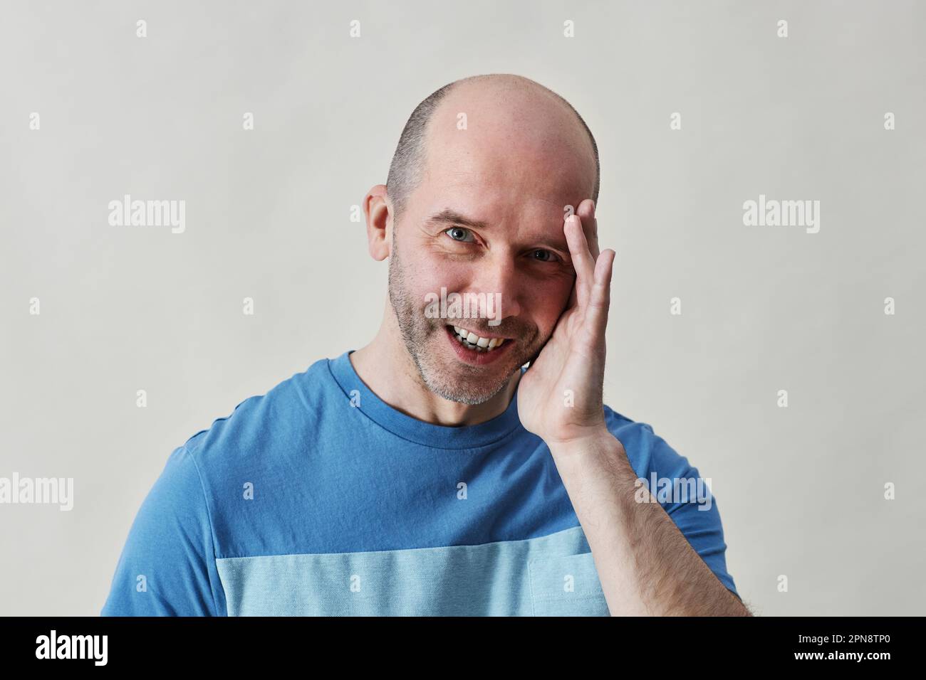 Minimal portrait of smiling bald man looking at camera in studio ...