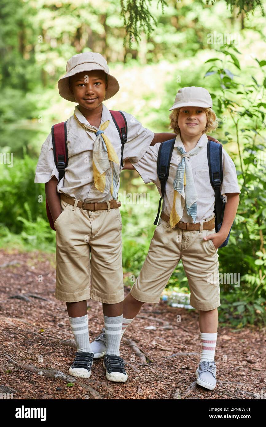 Vertical full length portrait of two cute boy scouts looking at camera ...