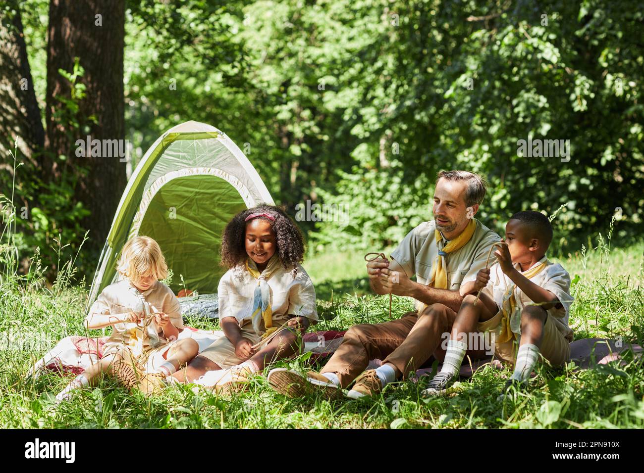 Full length view at group of young scouts with leader camping together ...
