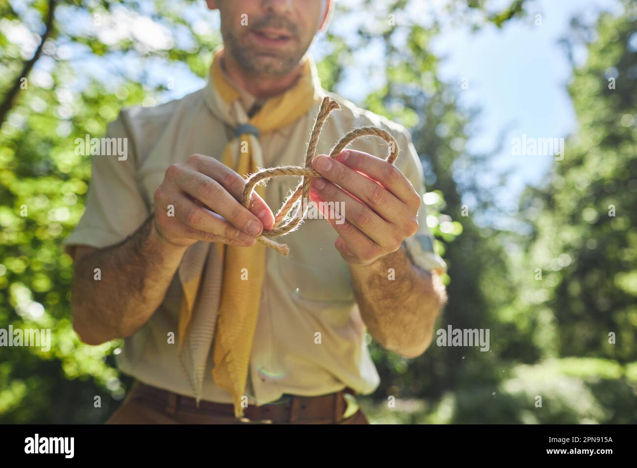 Close up of unrecognizable scout leader tying rope ouitdoors while ...